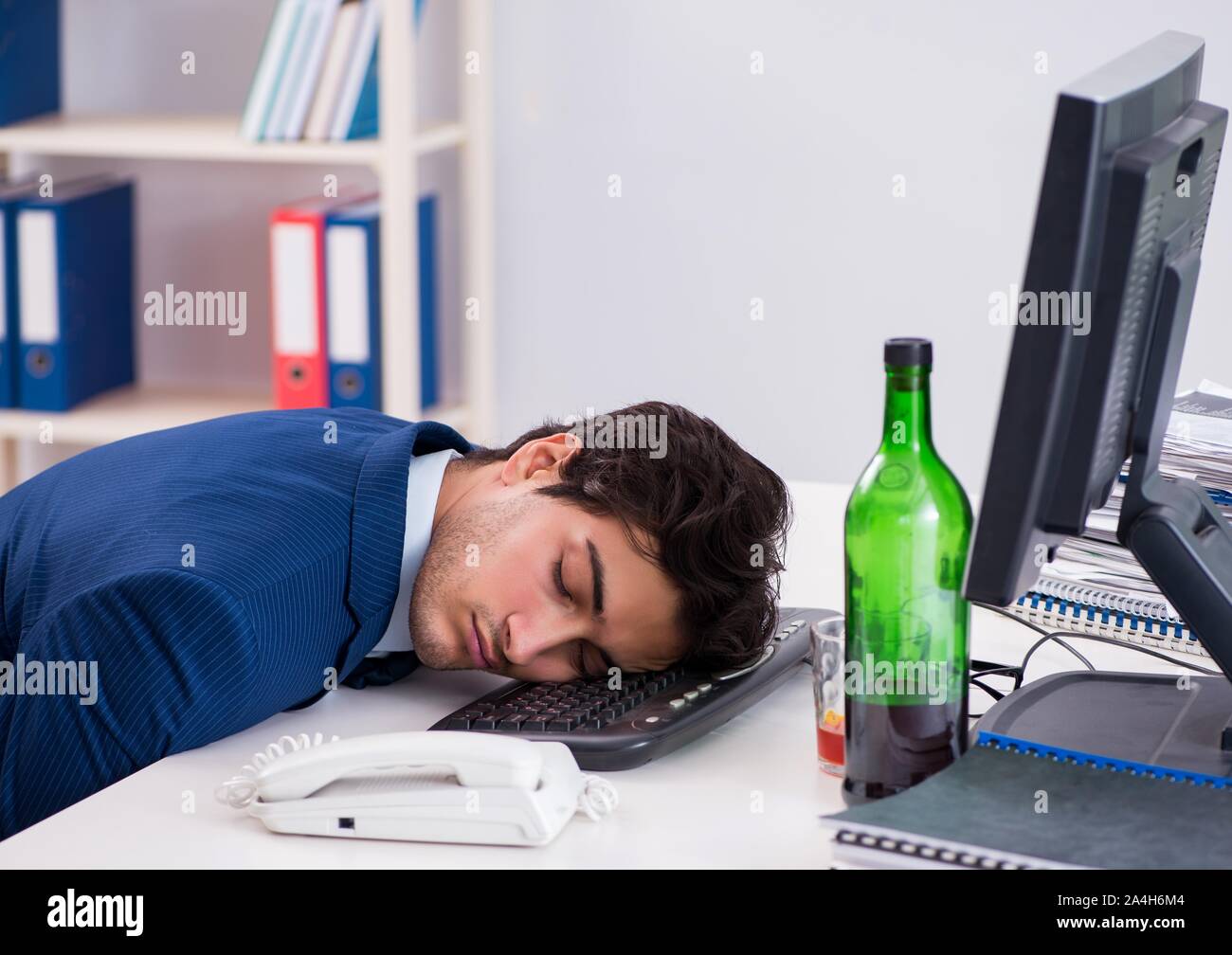 The young businessman employee drinking in the office at desk Stock ...