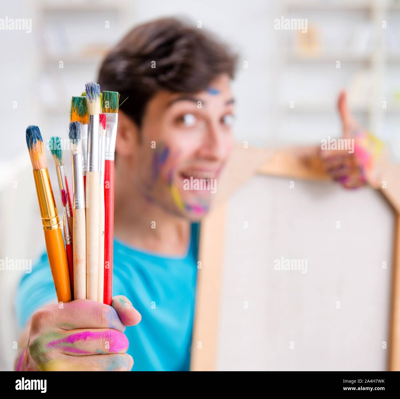 The young funny artist working on new painting in his studio Stock ...