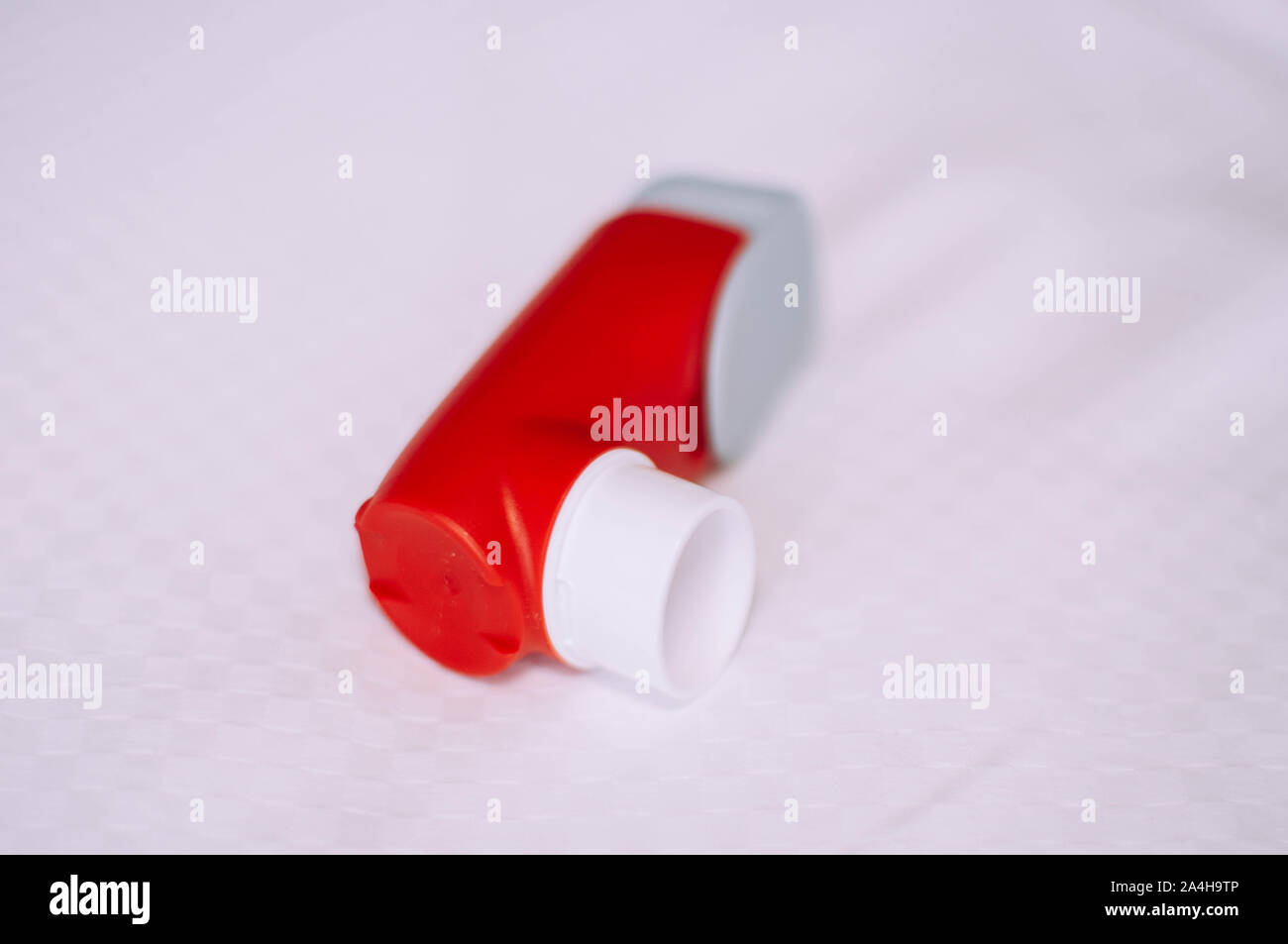 A still life of red and white asthma inhaler devise on a white ...