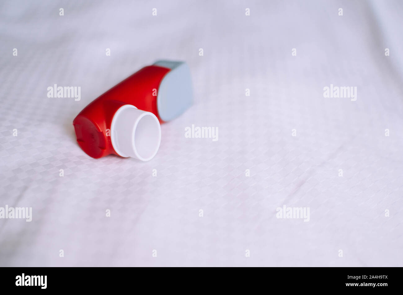 A still life of red and white asthma inhaler devise on a white ...