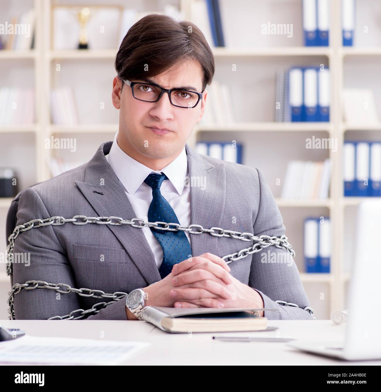 The businessman tied with chains to his work Stock Photo - Alamy