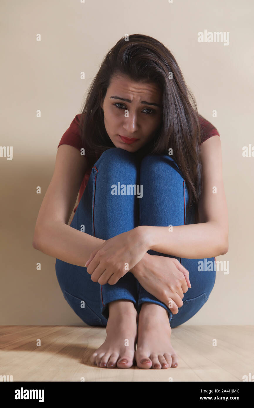 Young girl sitting alone in distress Stock Photo - Alamy
