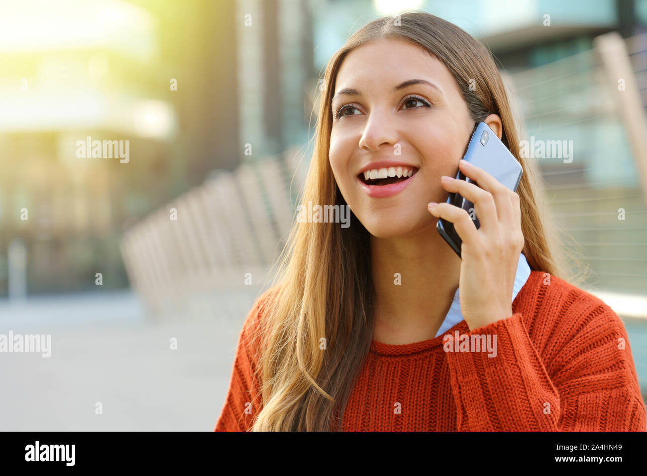 Pretty cheerful young woman talking on phone and looks straight ahead ...