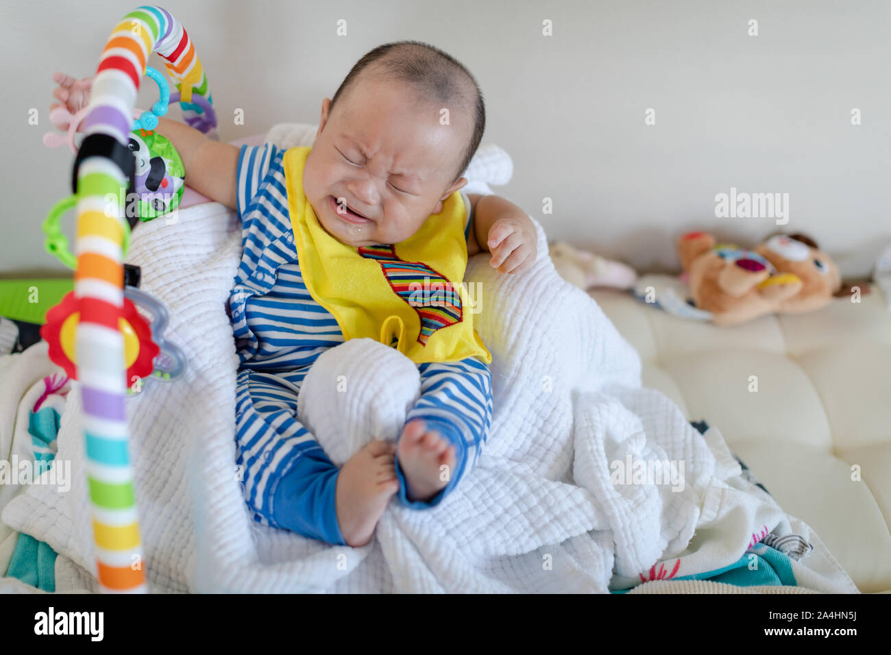 Angry baby boy sitting on play gym at home Stock Photo - Alamy