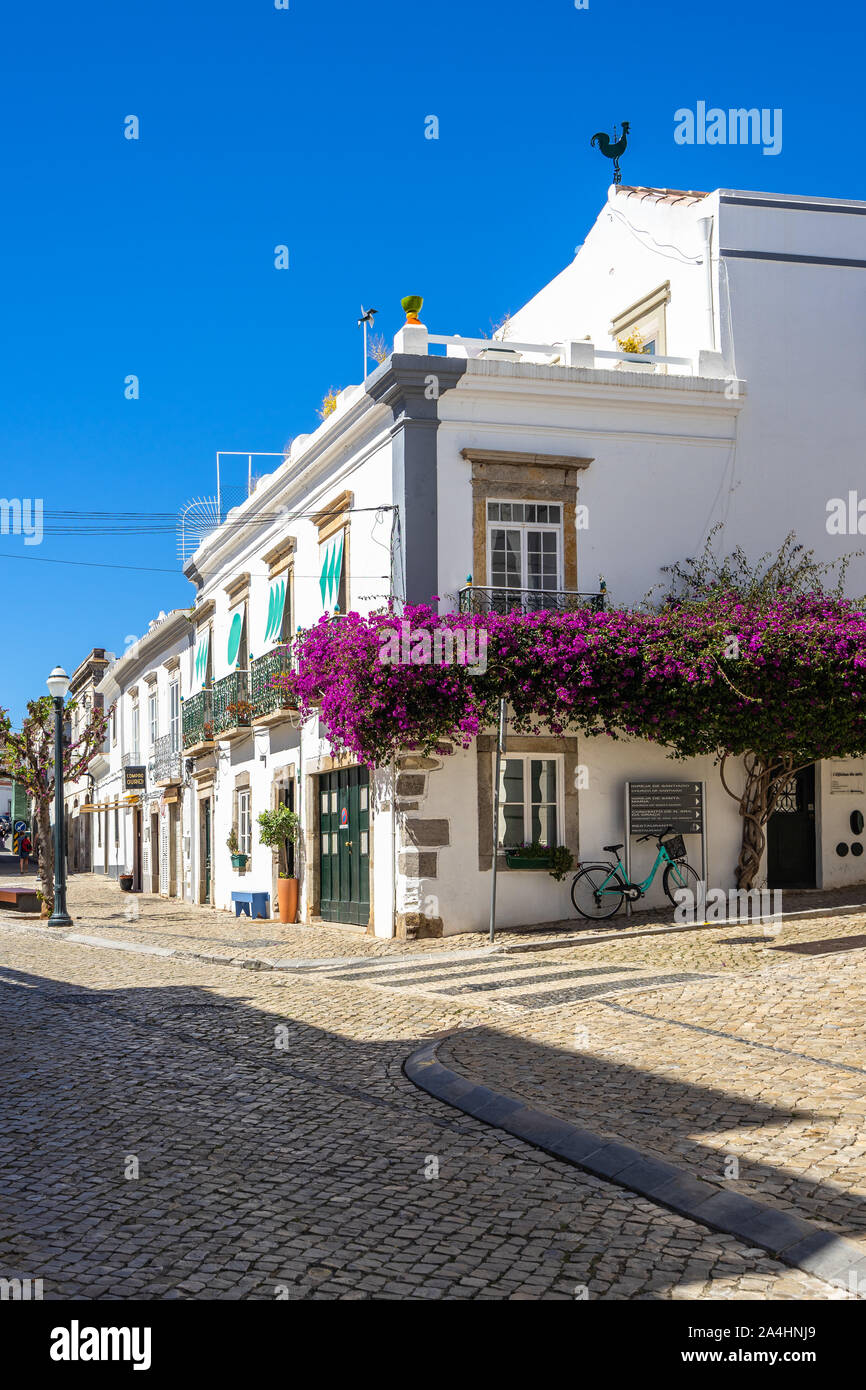 A picturesque street in Tavira with whitewashed houses decorated with ...