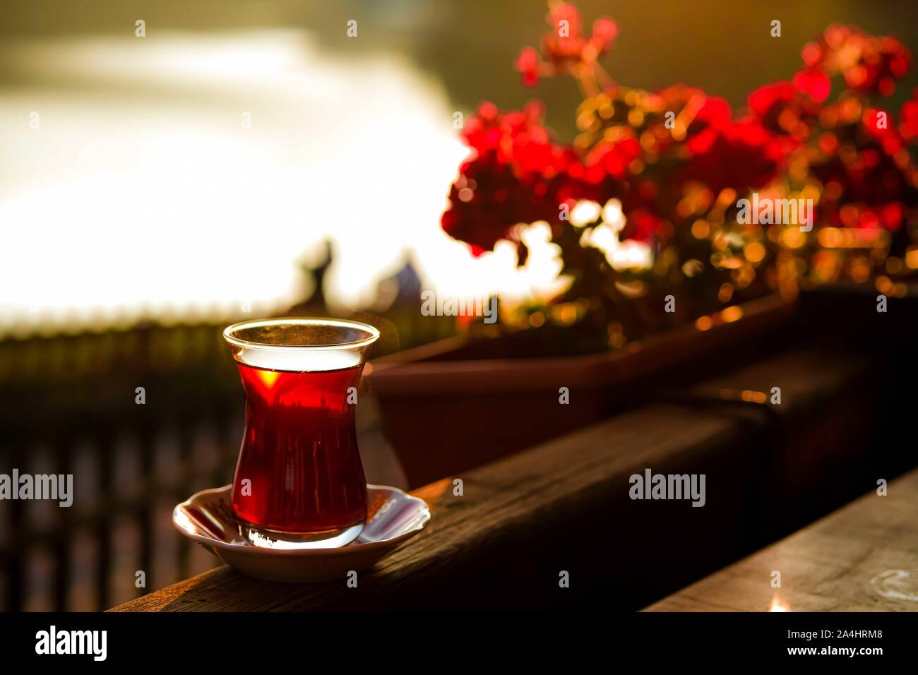 Turkish tea and beautiful sunset at the lake with red flowers ...