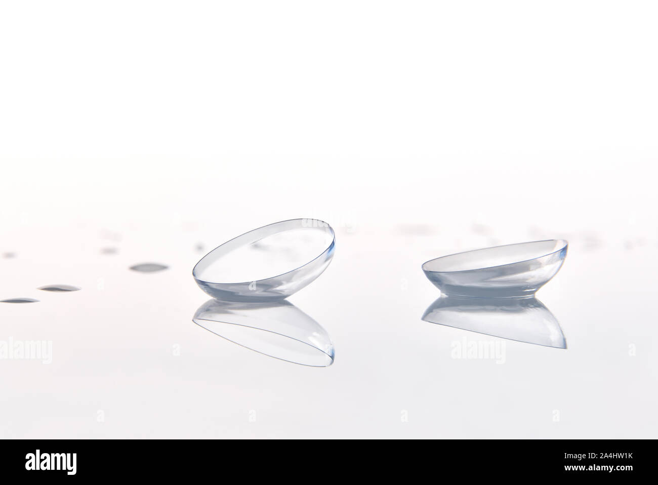 Contact lenses on glass reflective table with water drops and isolated ...
