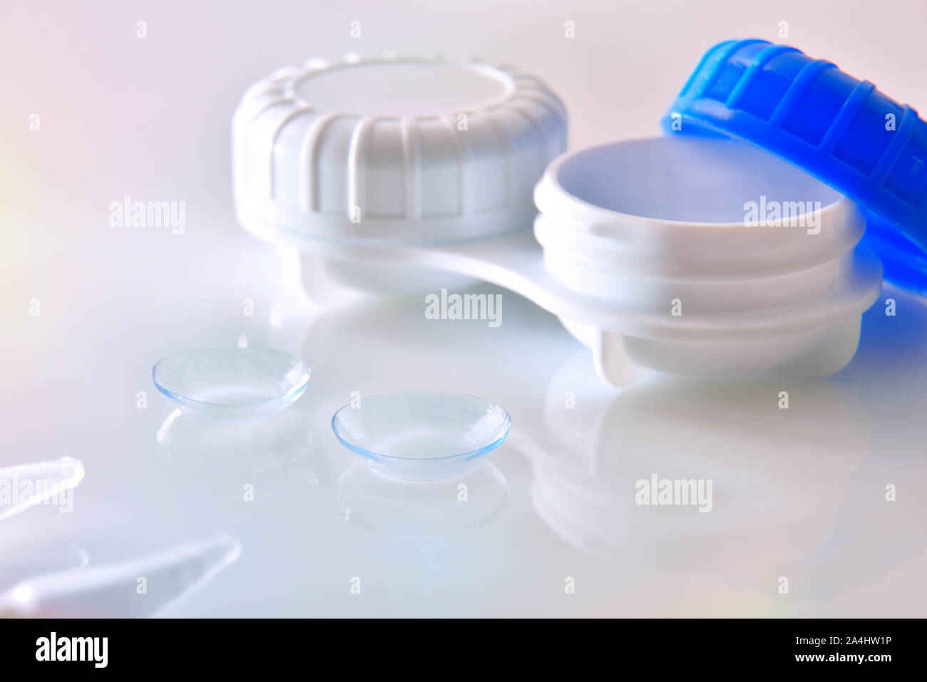 Contact lenses and case reflected on white glass table. Horizontal ...