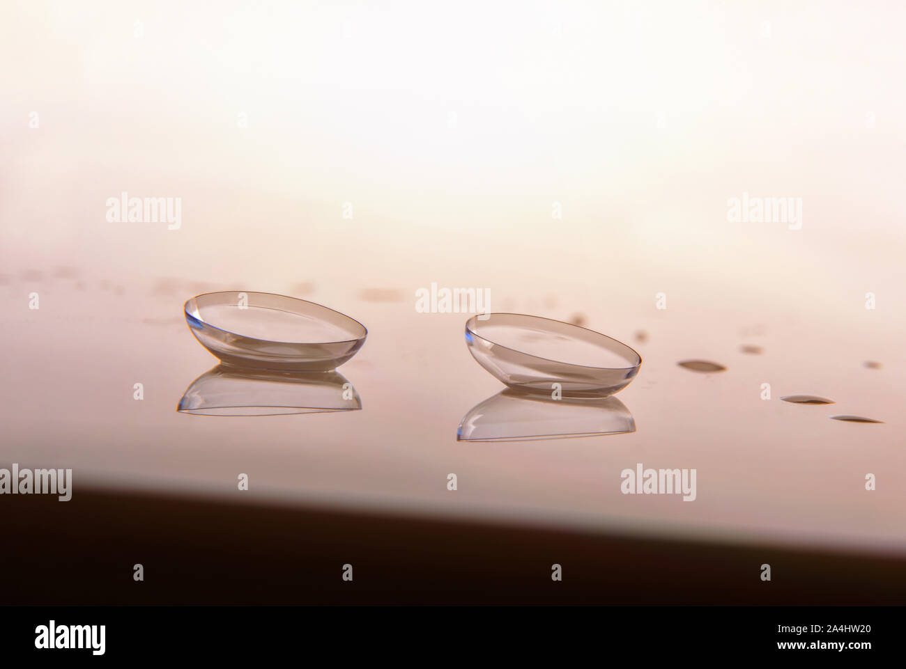 Contact lenses on glass reflective table with water drops and isolated ...