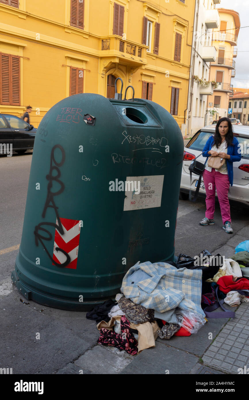 spilled clothing from recycling clothing bank bin pisa italy woman ...