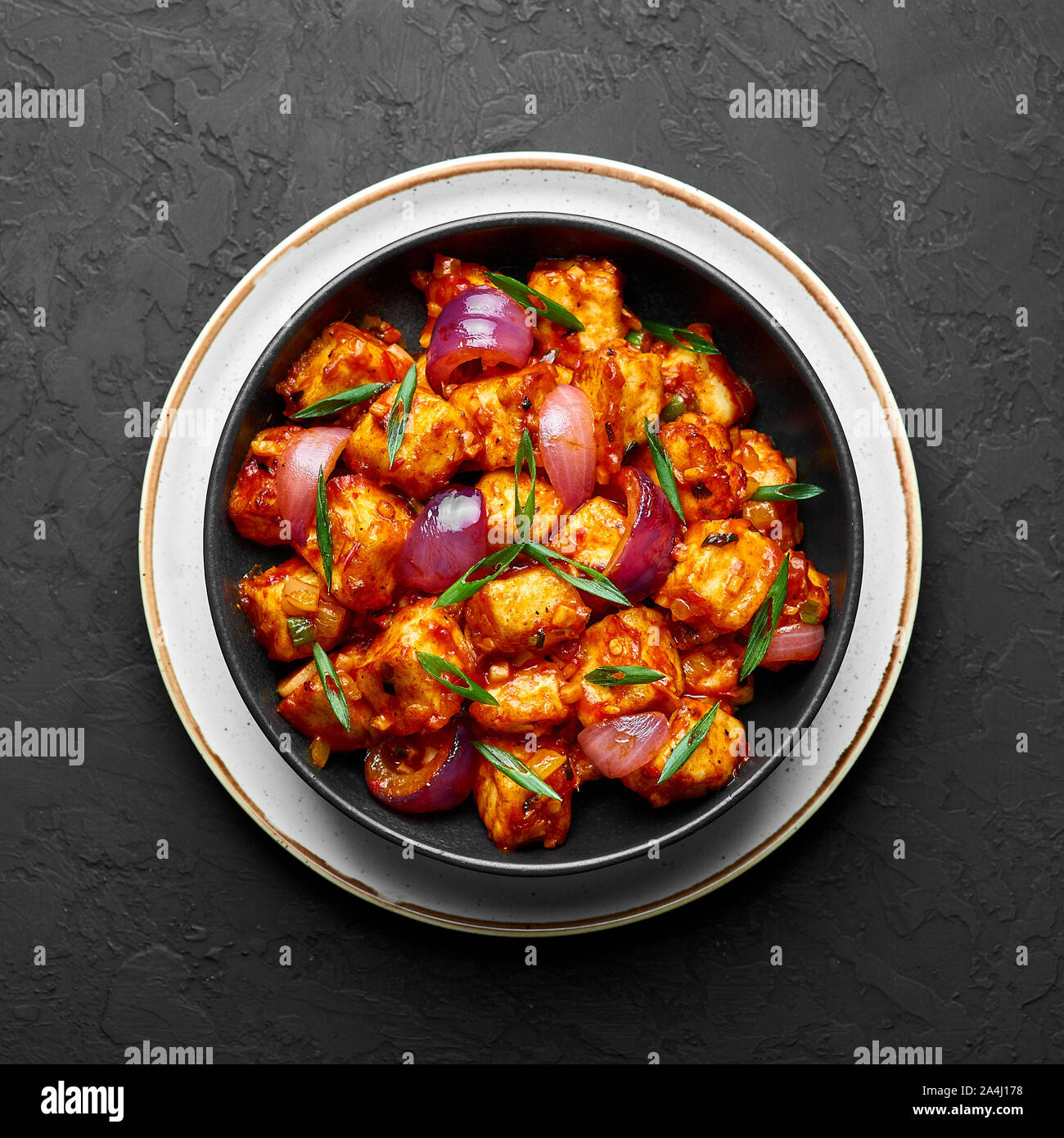 Schezwan Paneer in black bowl at dark slate background. Schezwan Paneer ...