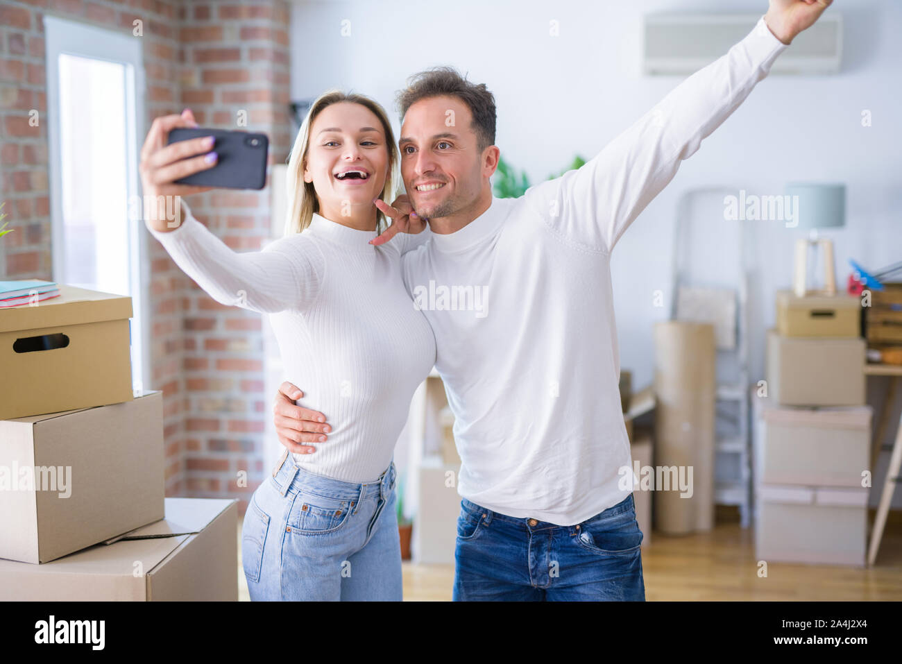 Young beautiful couple standing using smartphone to take selfie at new ...