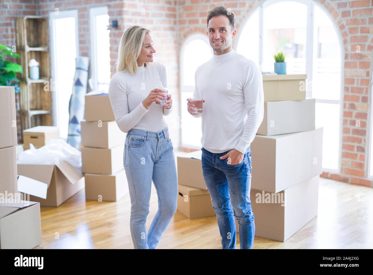 Young Beautiful Couple Standing Drinking Cup Of Coffee At New Home