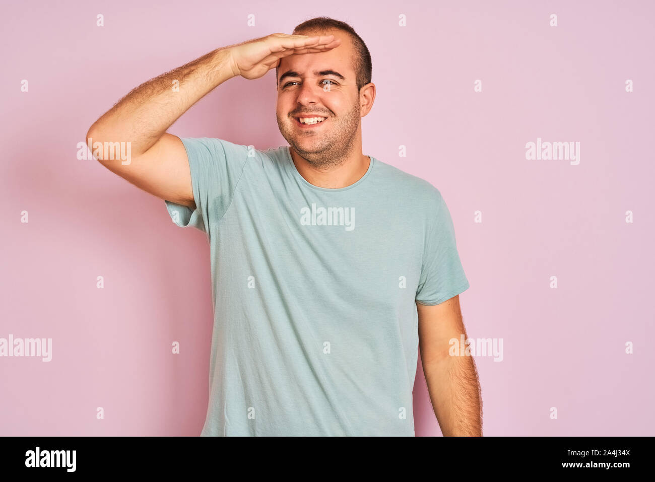 Young man wearing blue casual t-shirt standing over isolated pink ...