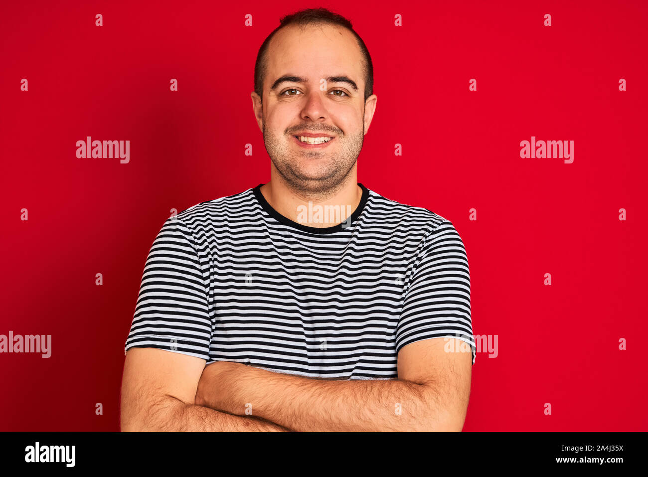 Young man wearing striped navy t-shirt standing over isolated red ...
