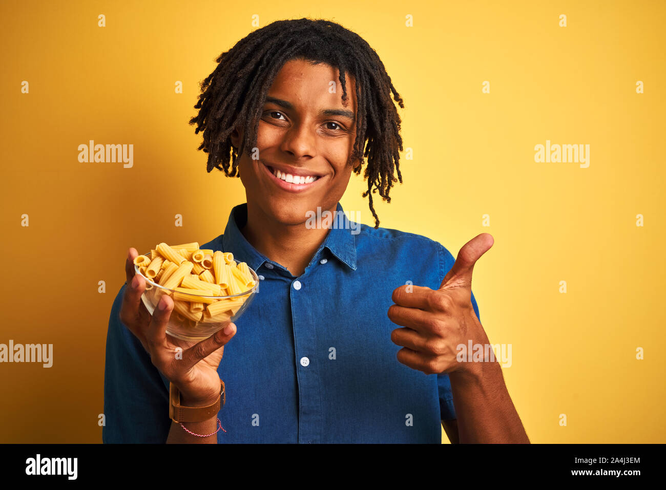 Afro american man with dreadlocks holding pasta macaroni over isolated ...