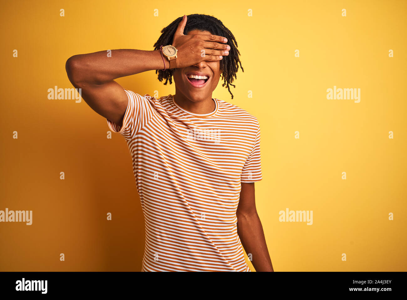 Afro man with dreadlocks wearing striped t-shirt standing over isolated ...