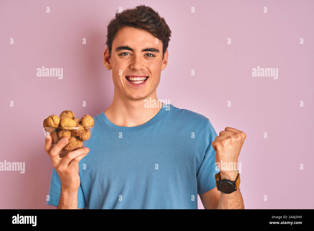Teenager boy holding bunch of natural walnuts over pink isolated ...