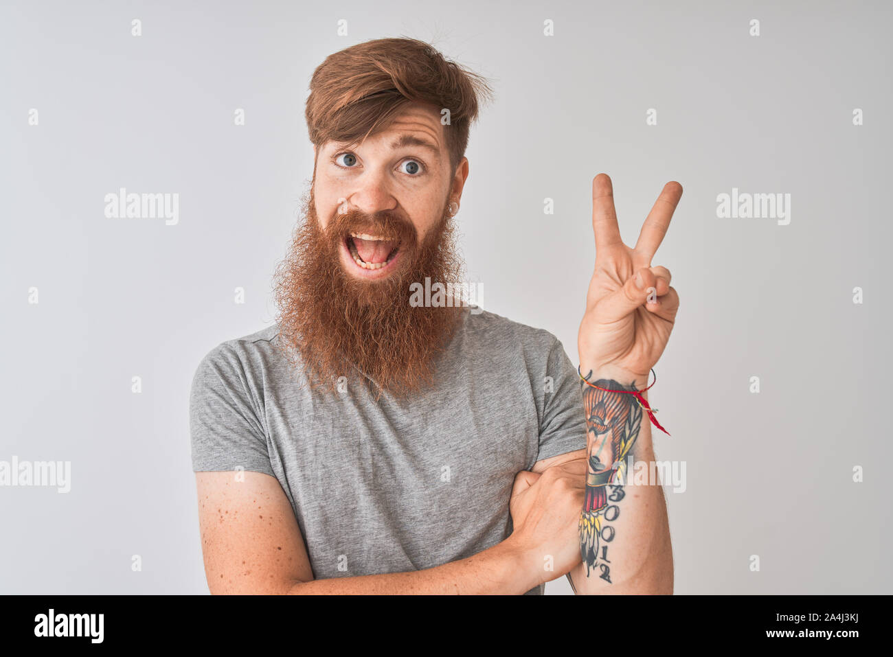Young redhead irish man wearing t-shirt standing over isolated grey ...