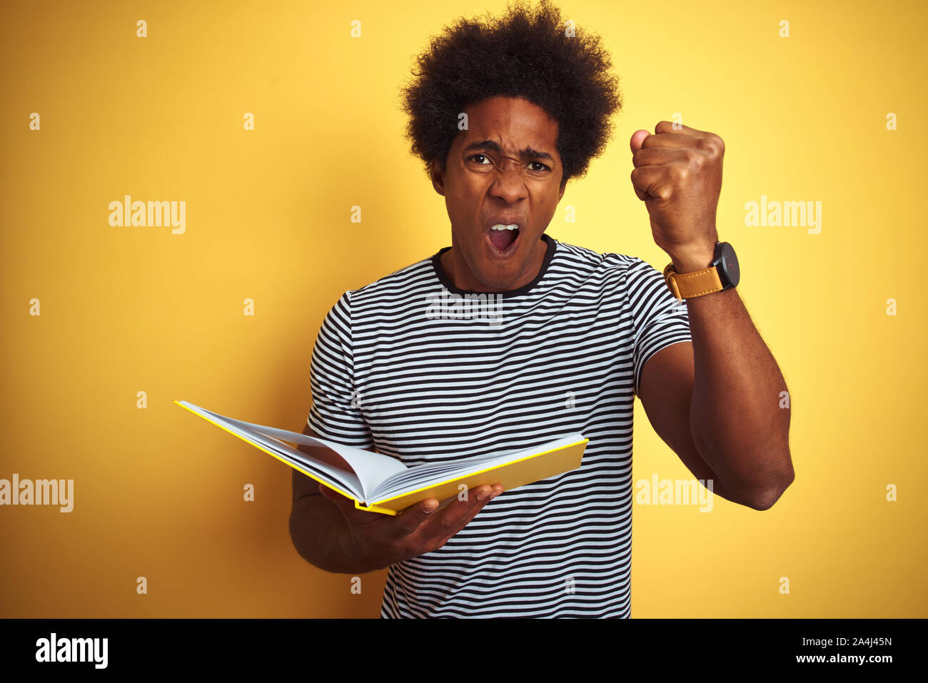 Afro american student man reading book standing over isolated yellow ...