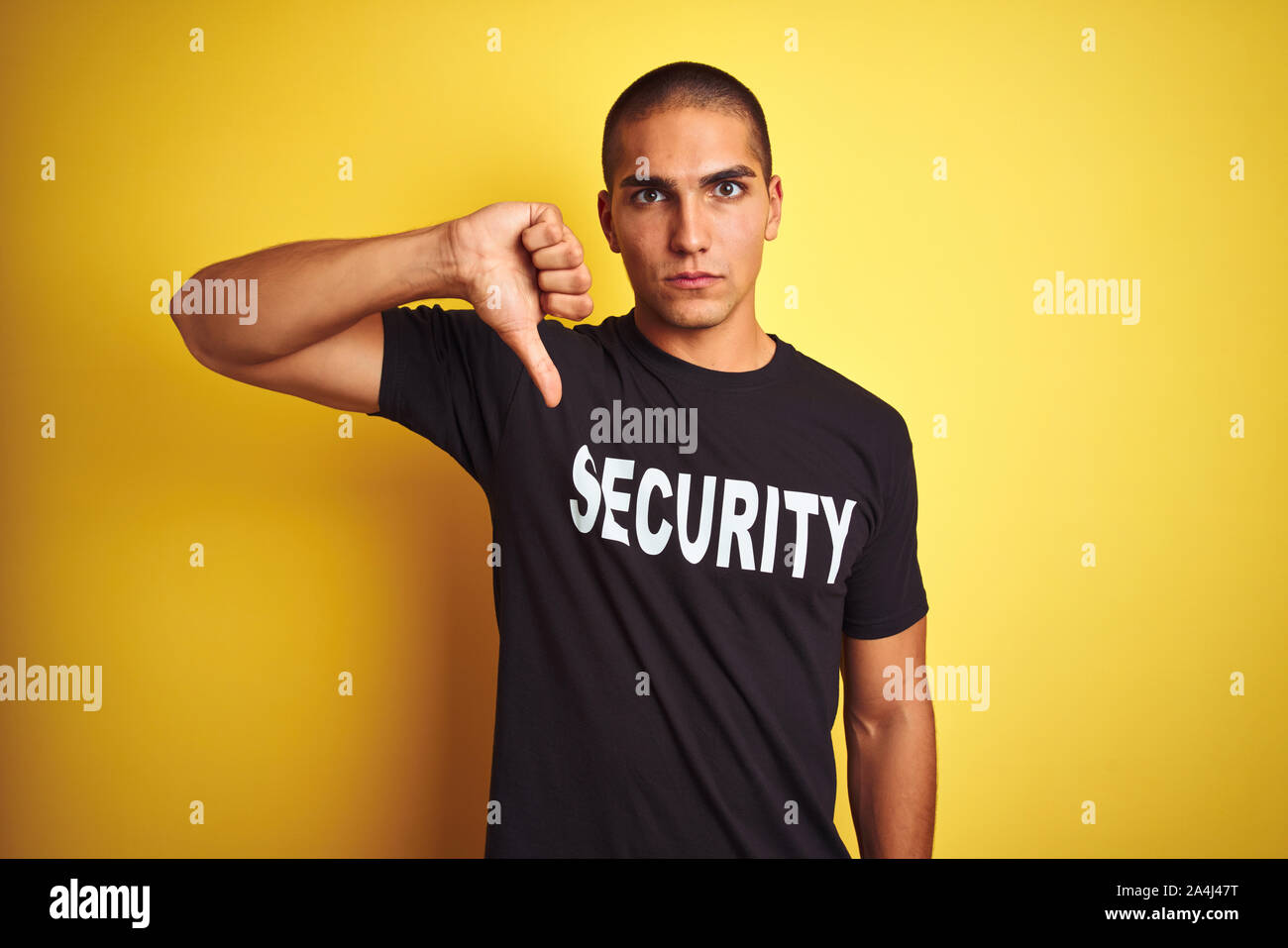 Young safeguard man with security t-shirt over yellow isolated ...