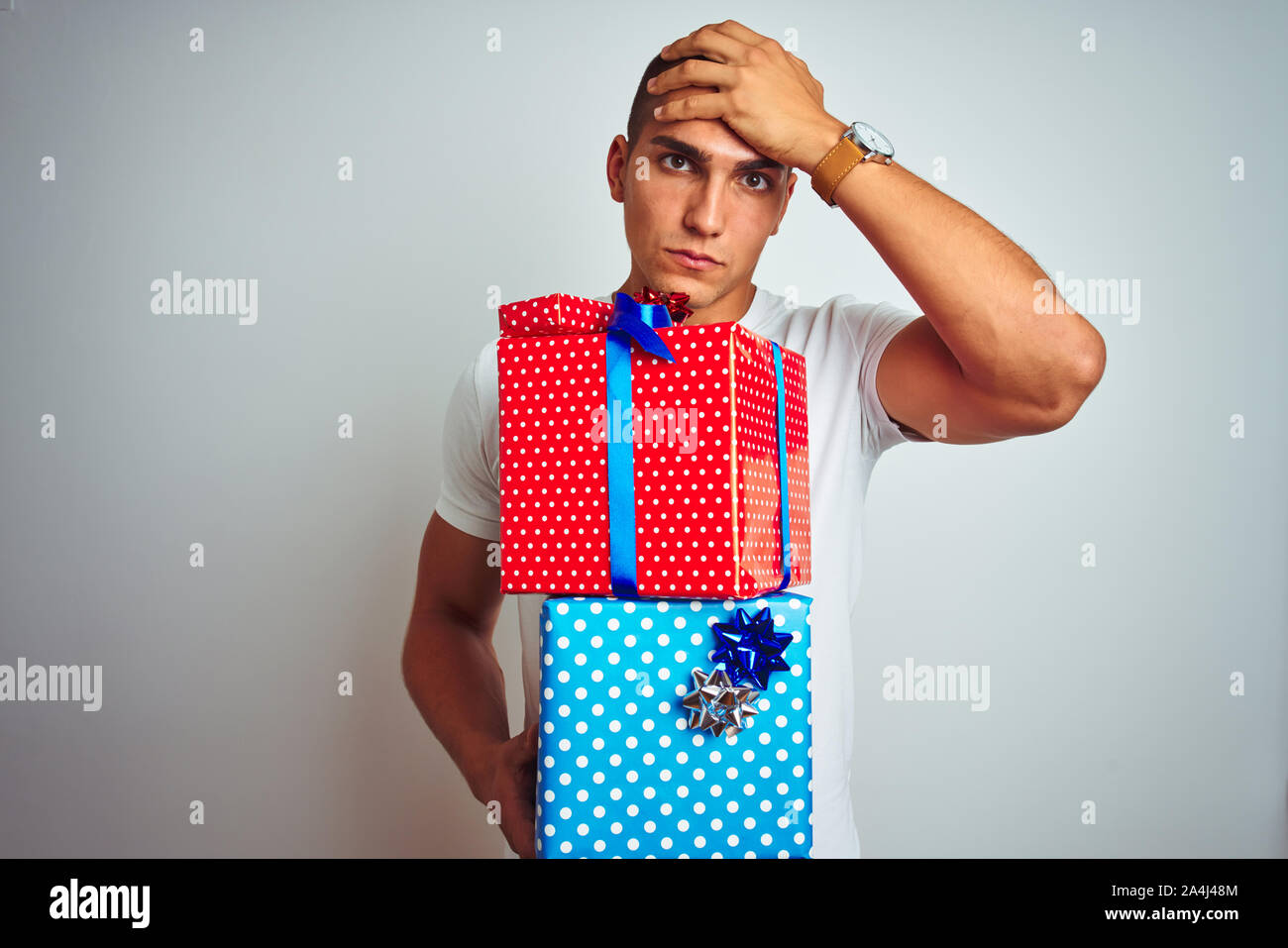 Young handsome man holding birthday gifts over white isolated ...