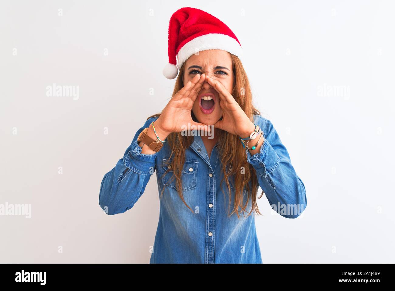 Young beautiful redhead woman wearing christmas hat over isolated ...