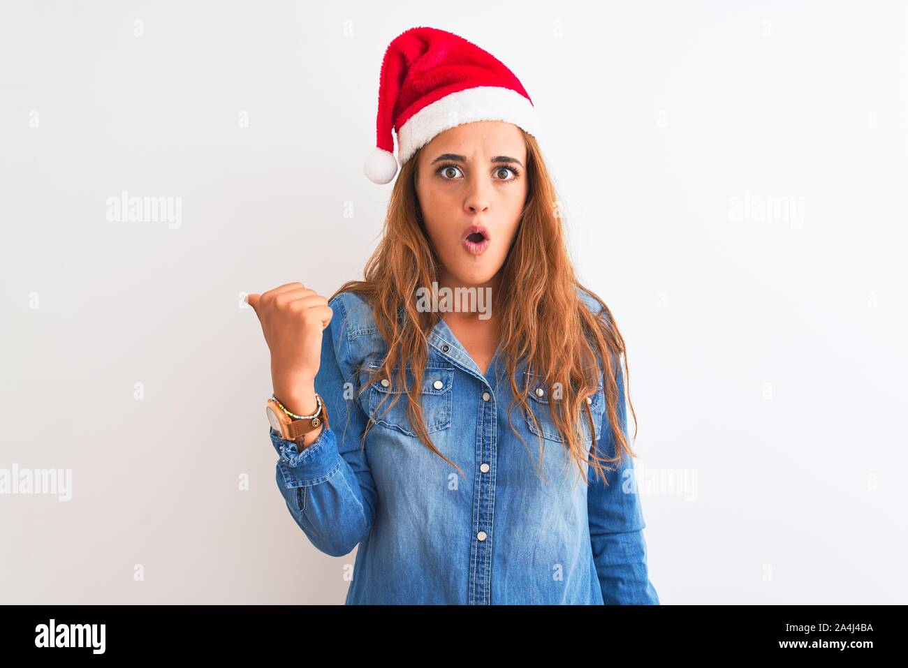 Young beautiful redhead woman wearing christmas hat over isolated ...