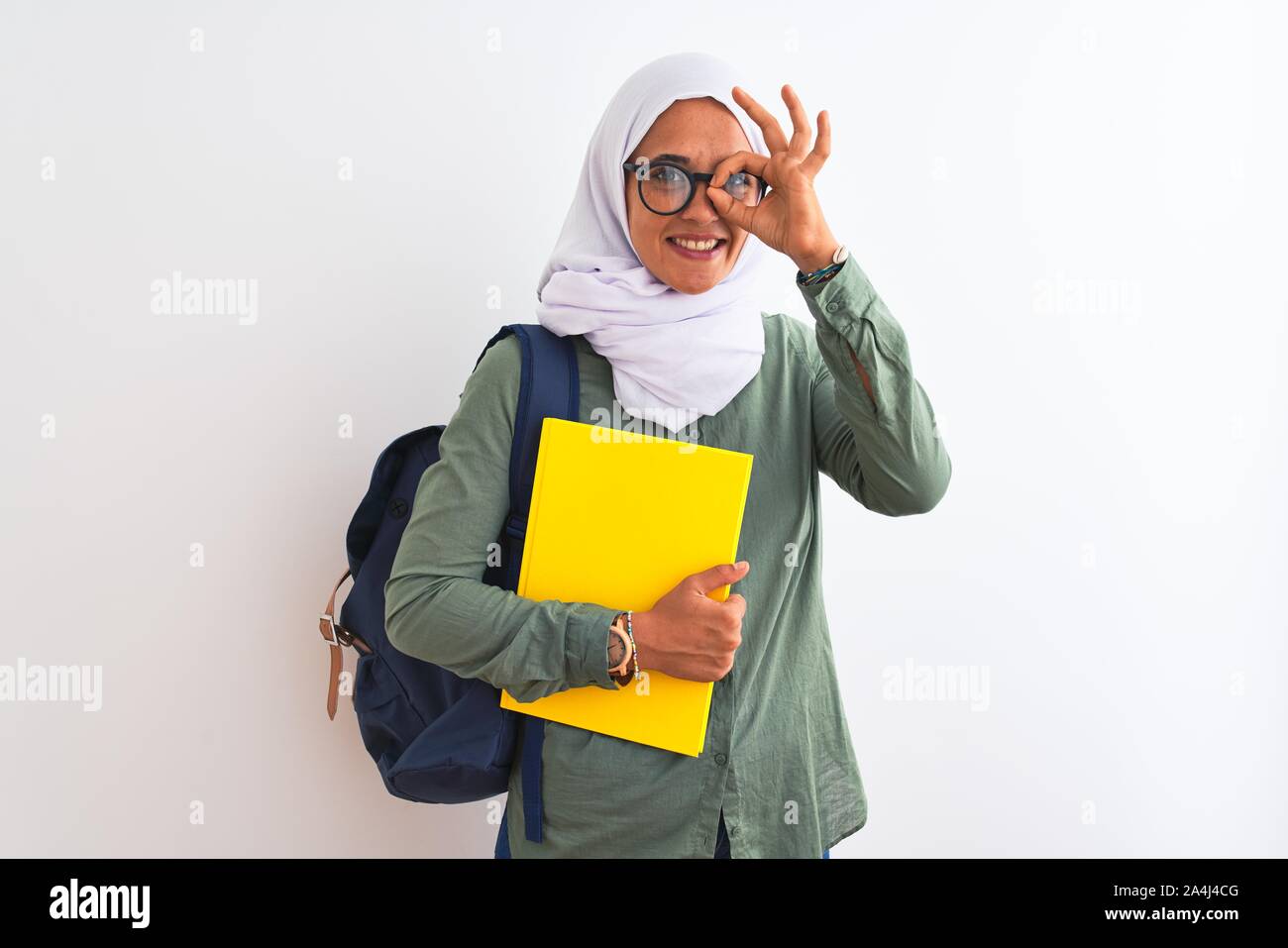 Young Arab student woman wearing hijab and backpack holding a book over ...