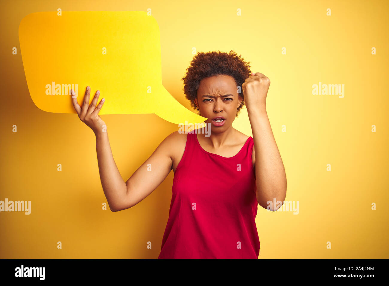 Young african american woman holding speech bubble over yellow isolated ...