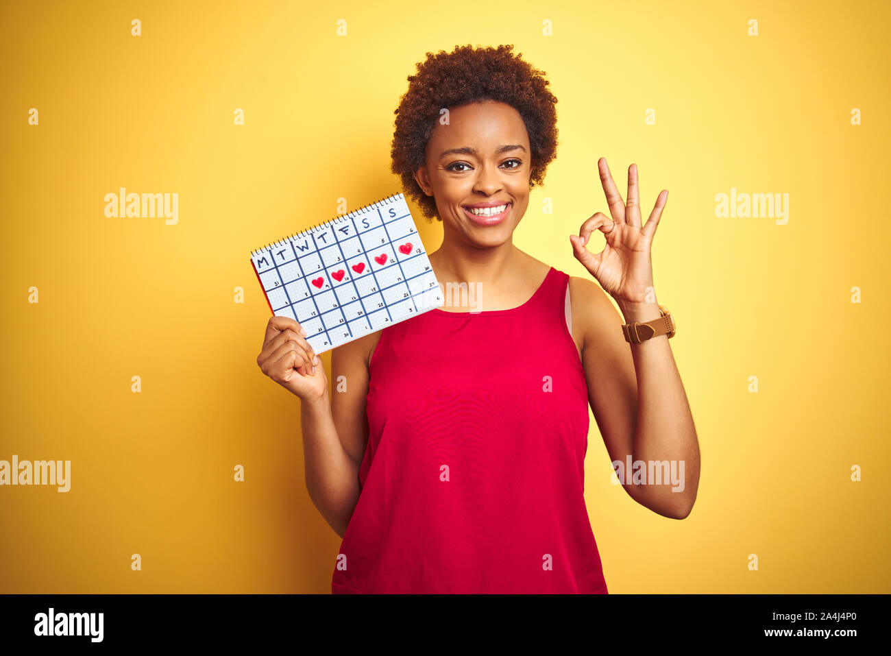 Young african american woman holding menstruation calendar over ...
