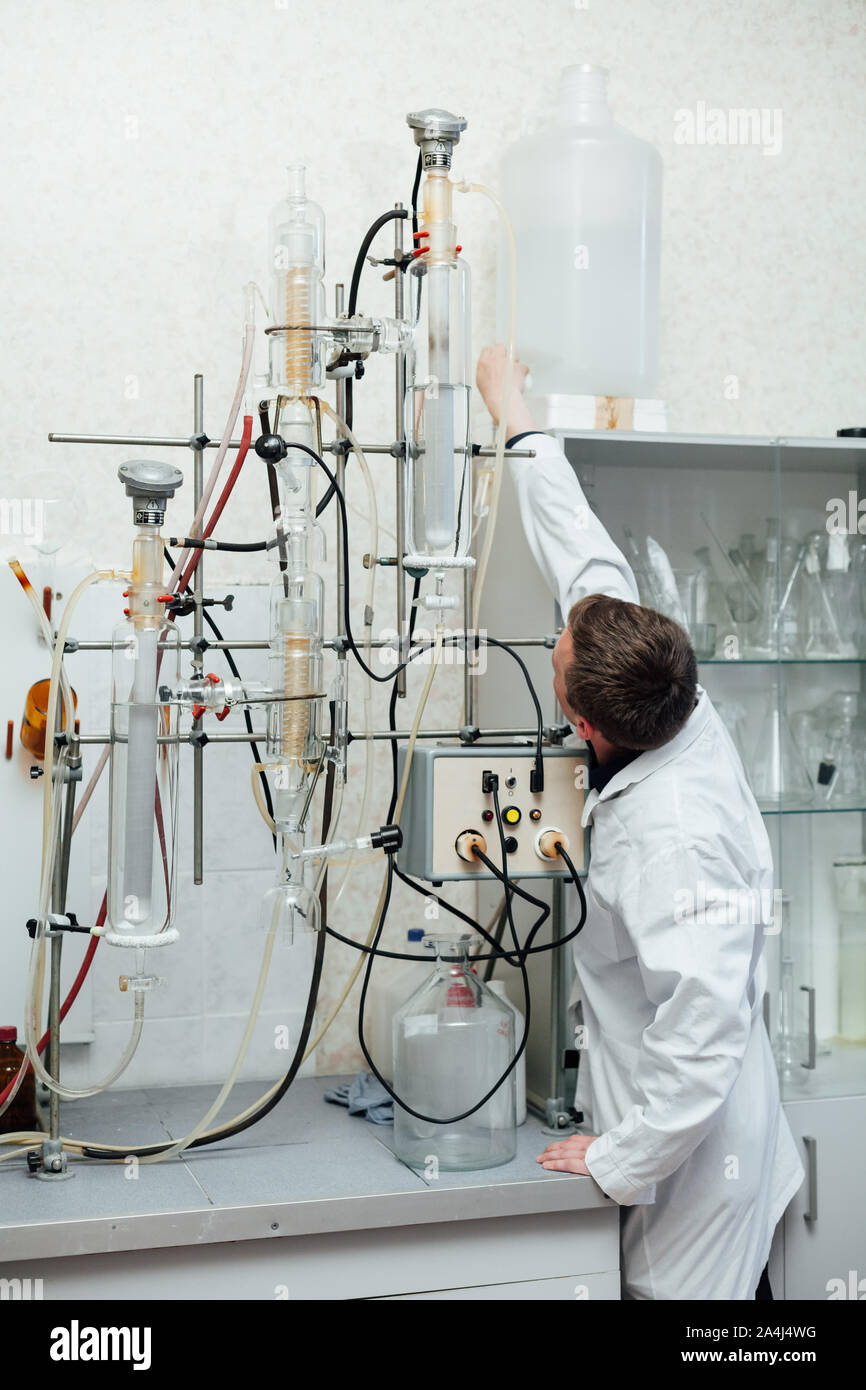 male young scientist conducts chemical experiments with liquids in lab ...