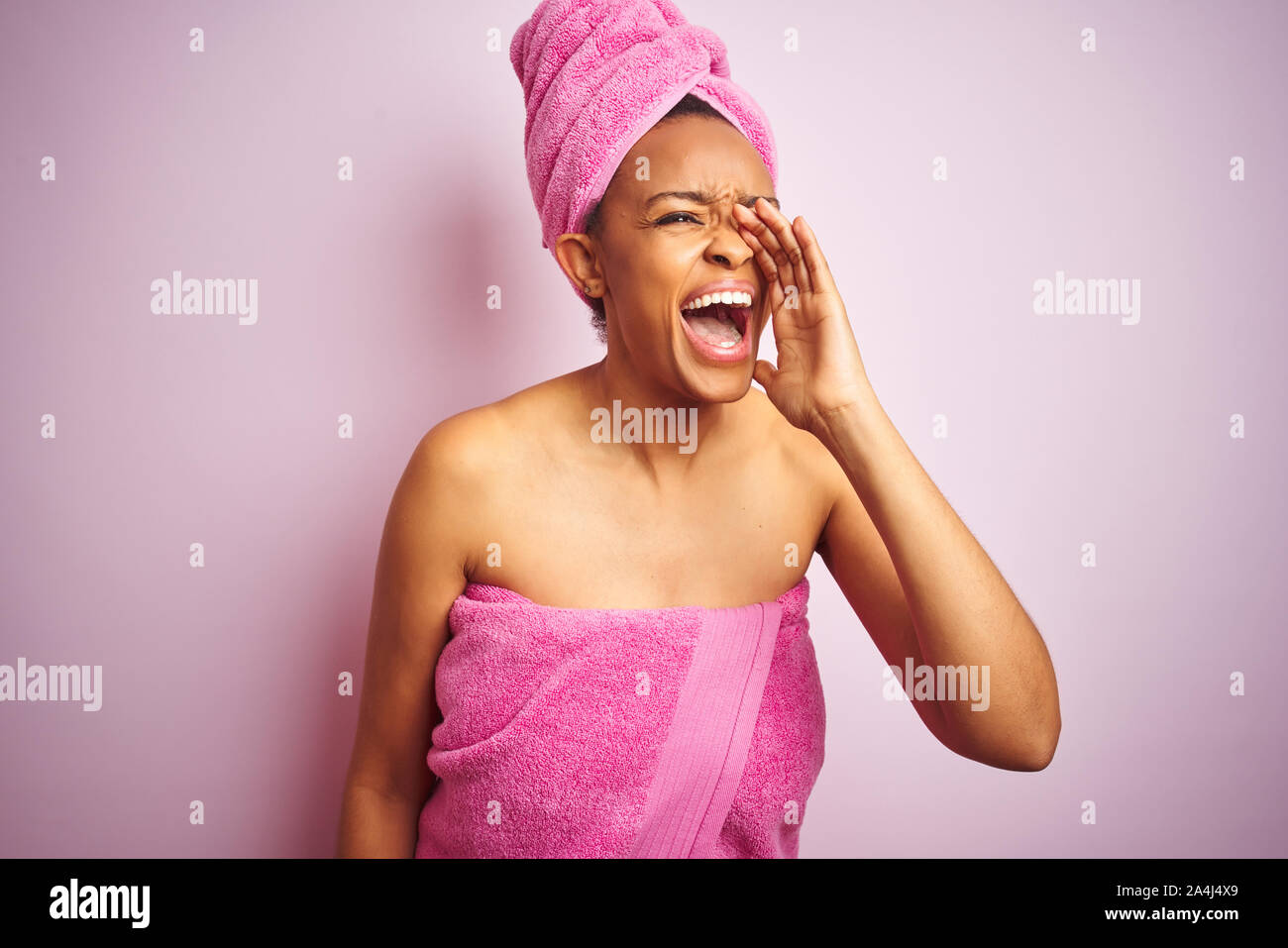 African american woman wearing shower towel after bath over pink ...
