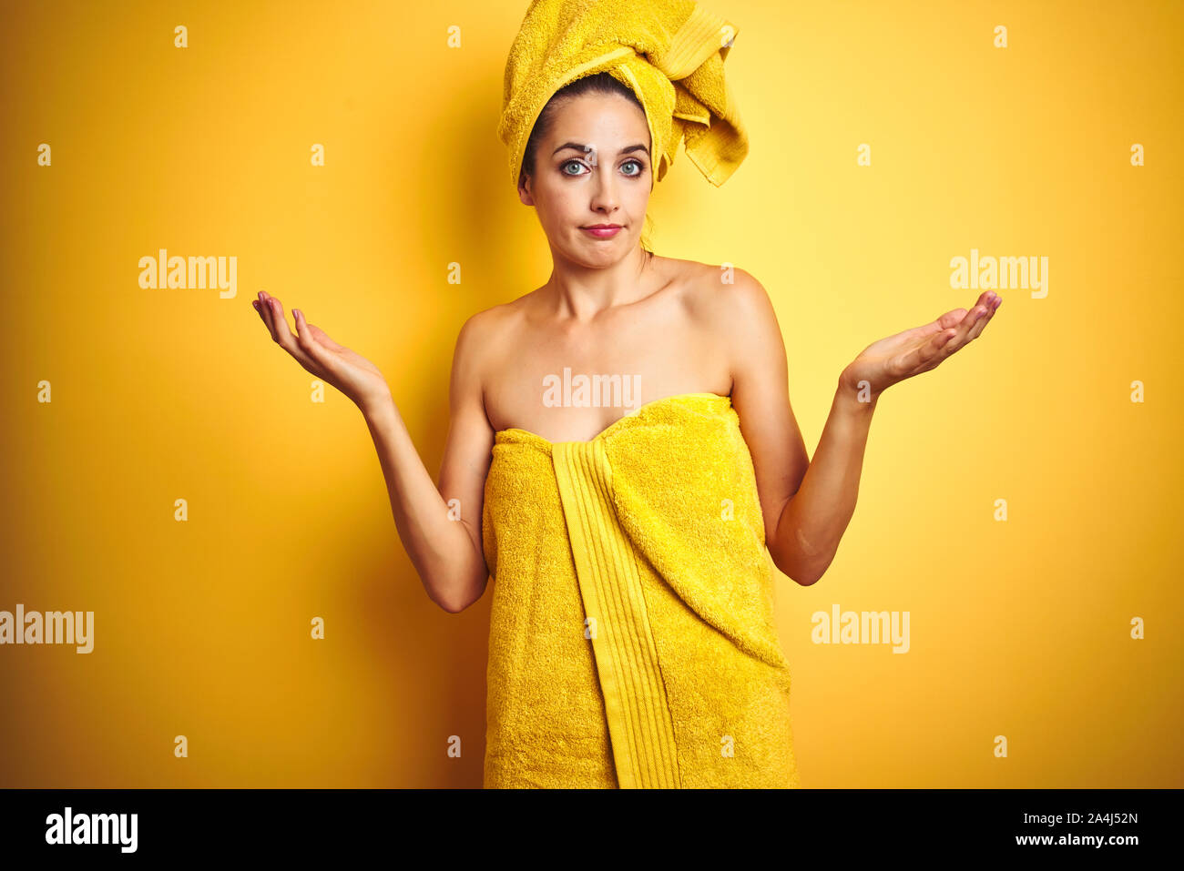 Beautiful woman wearing shower towel on body and head over yellow ...