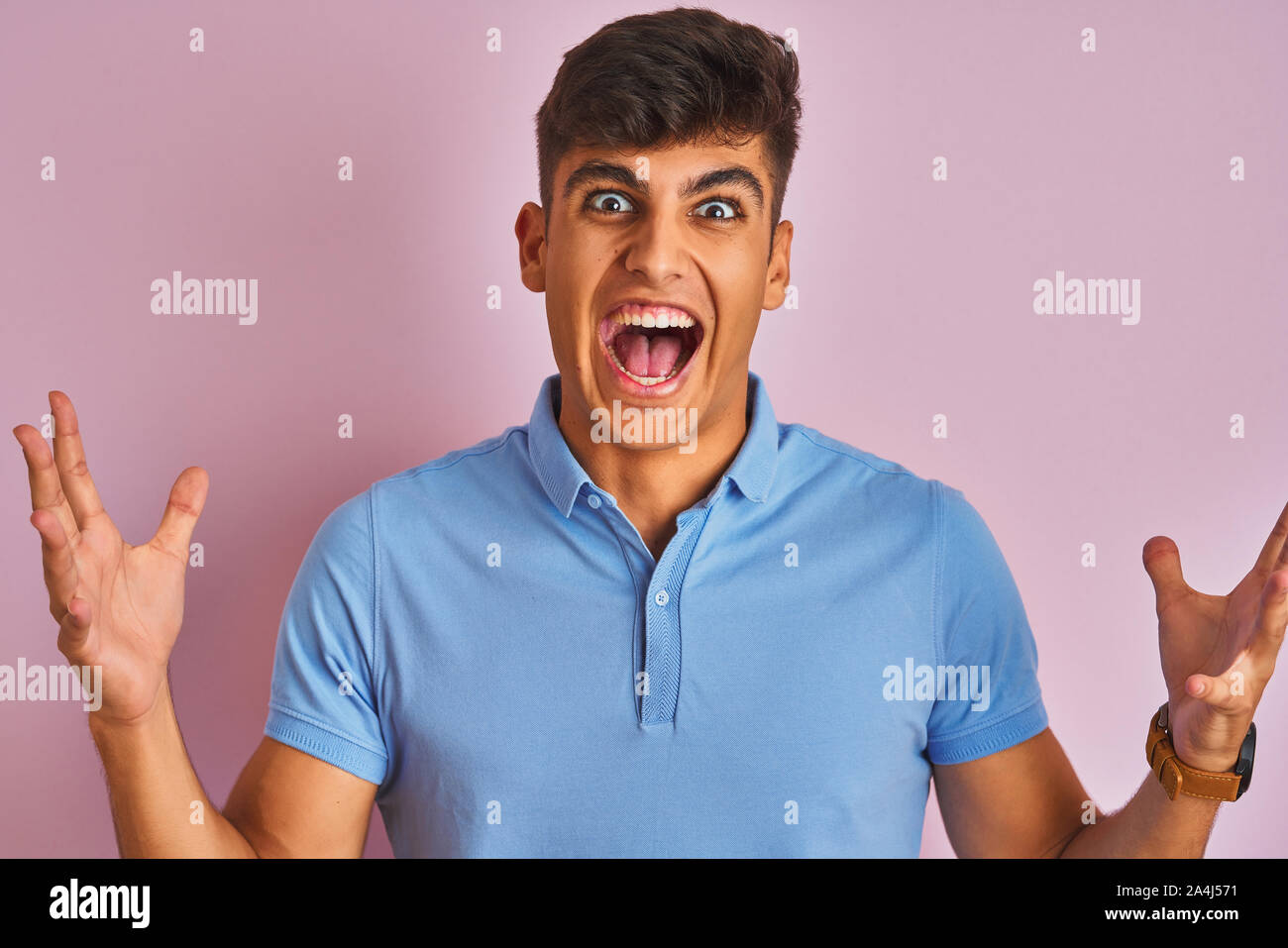Young indian man wearing blue polo standing over isolated pink ...