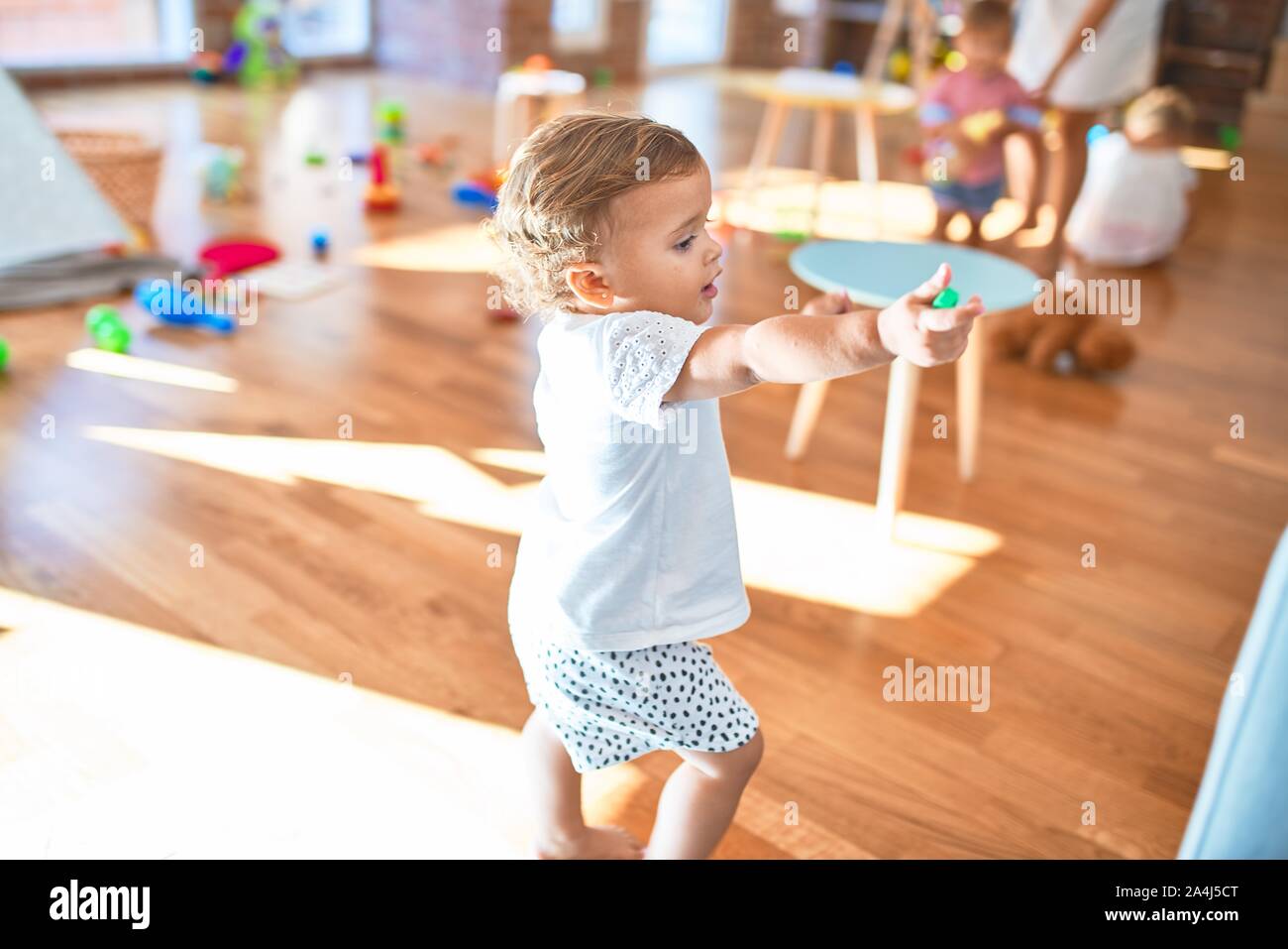 Adorable toddlers playing around lots of toys at kindergarten Stock ...