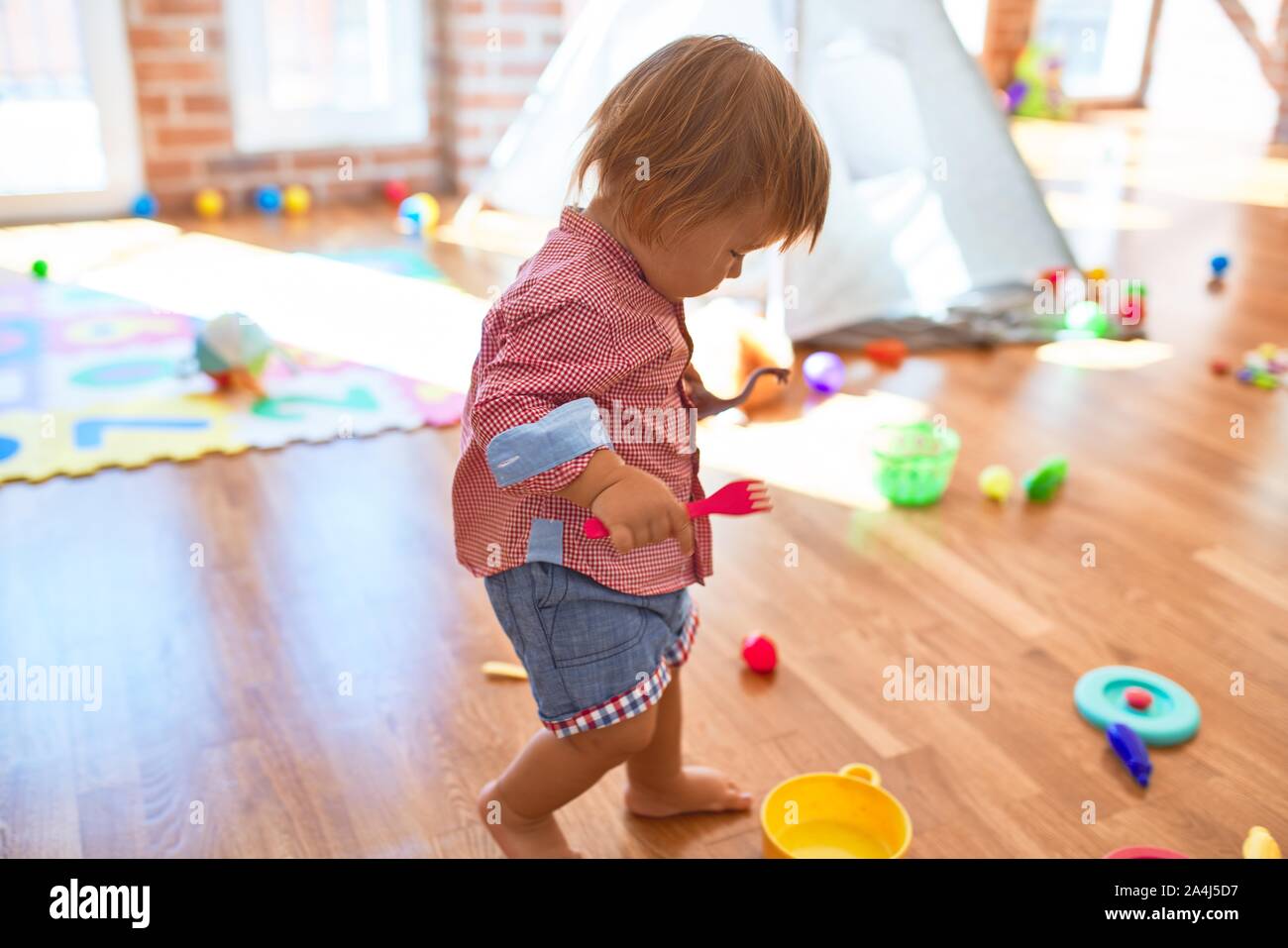 Adorable toddler playing around lots of toys at kindergarten Stock ...