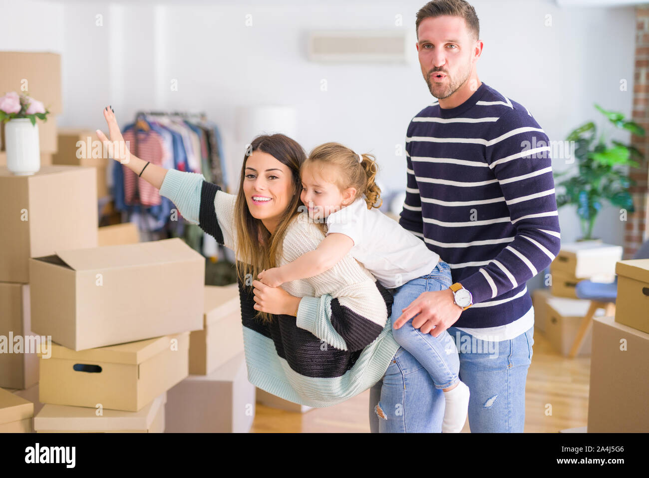 Beautiful family with a kid standing at new home around cardboard boxes ...