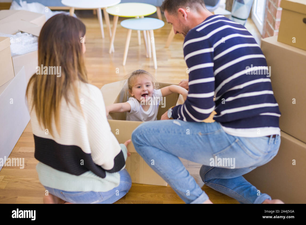 Beautiful famiily, kid playing with his parents riding cardboard fanny ...