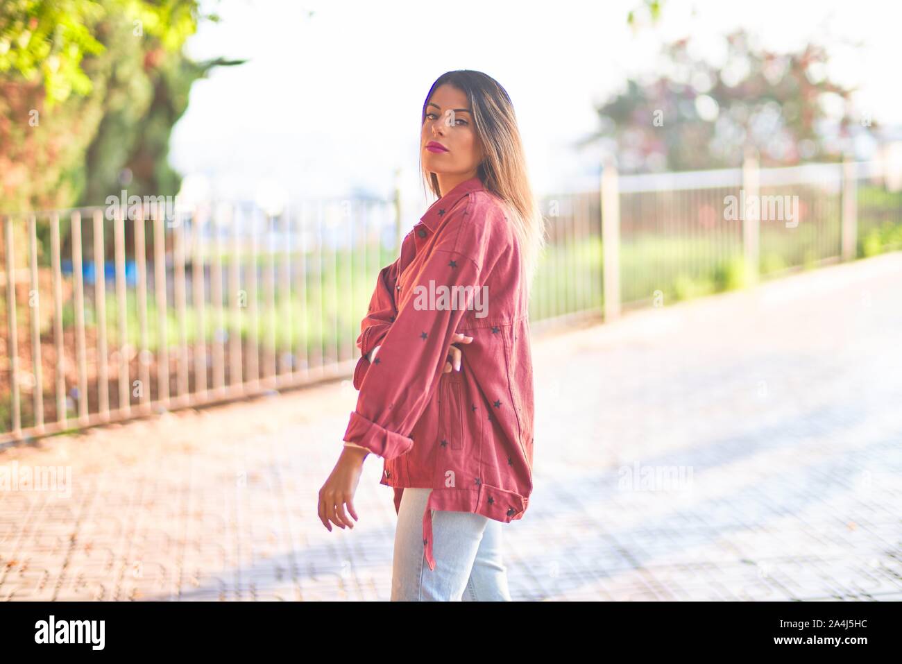 Young beautiful woman wearing red jacket standing at the town street ...