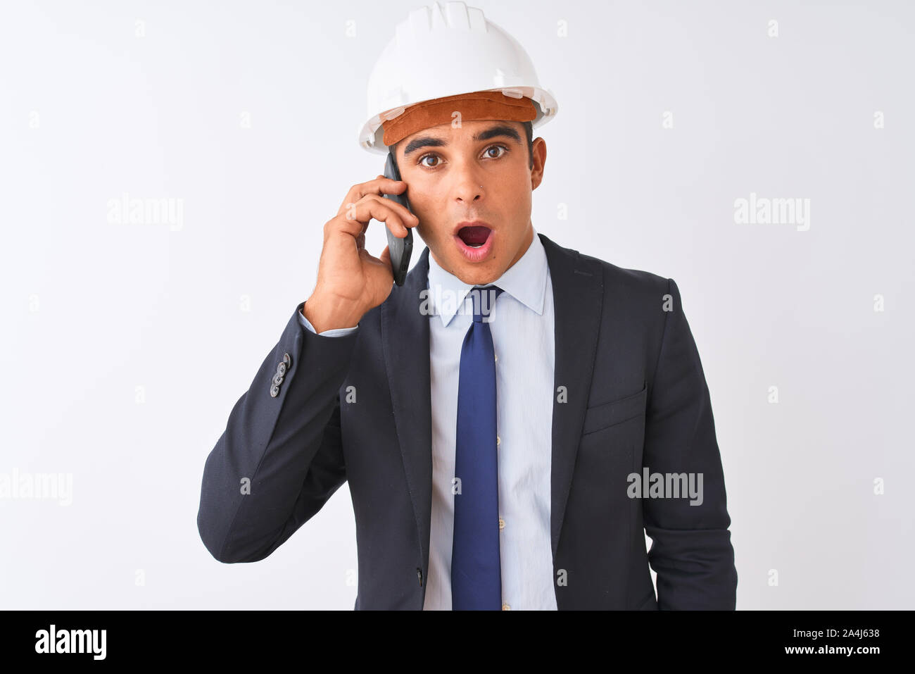 Young architect man wearing helmet talking on smartphone over isolated ...
