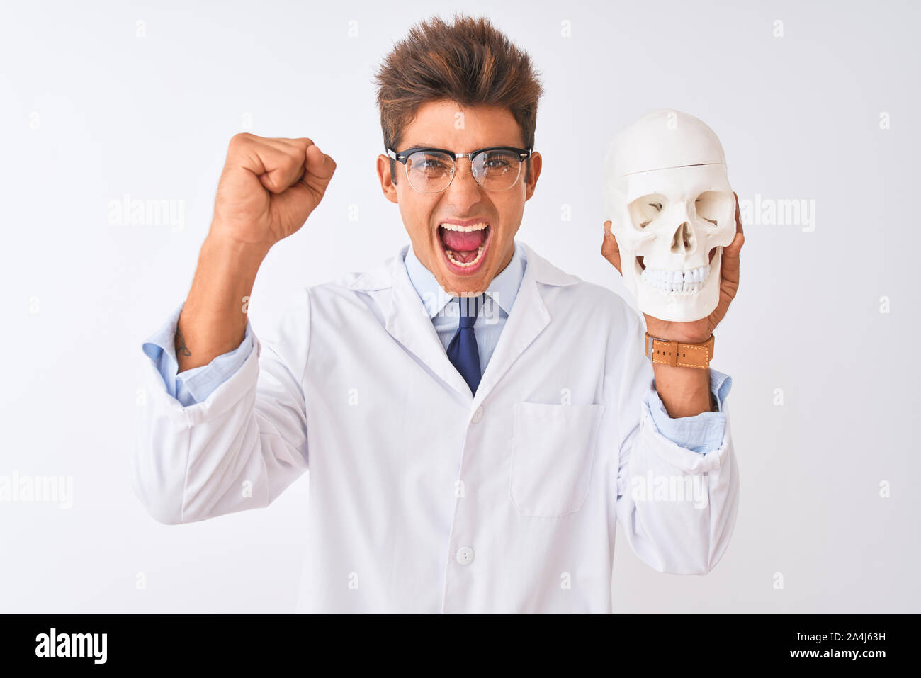 Young handsome doctor man wearing glasses holding skull over isolated ...