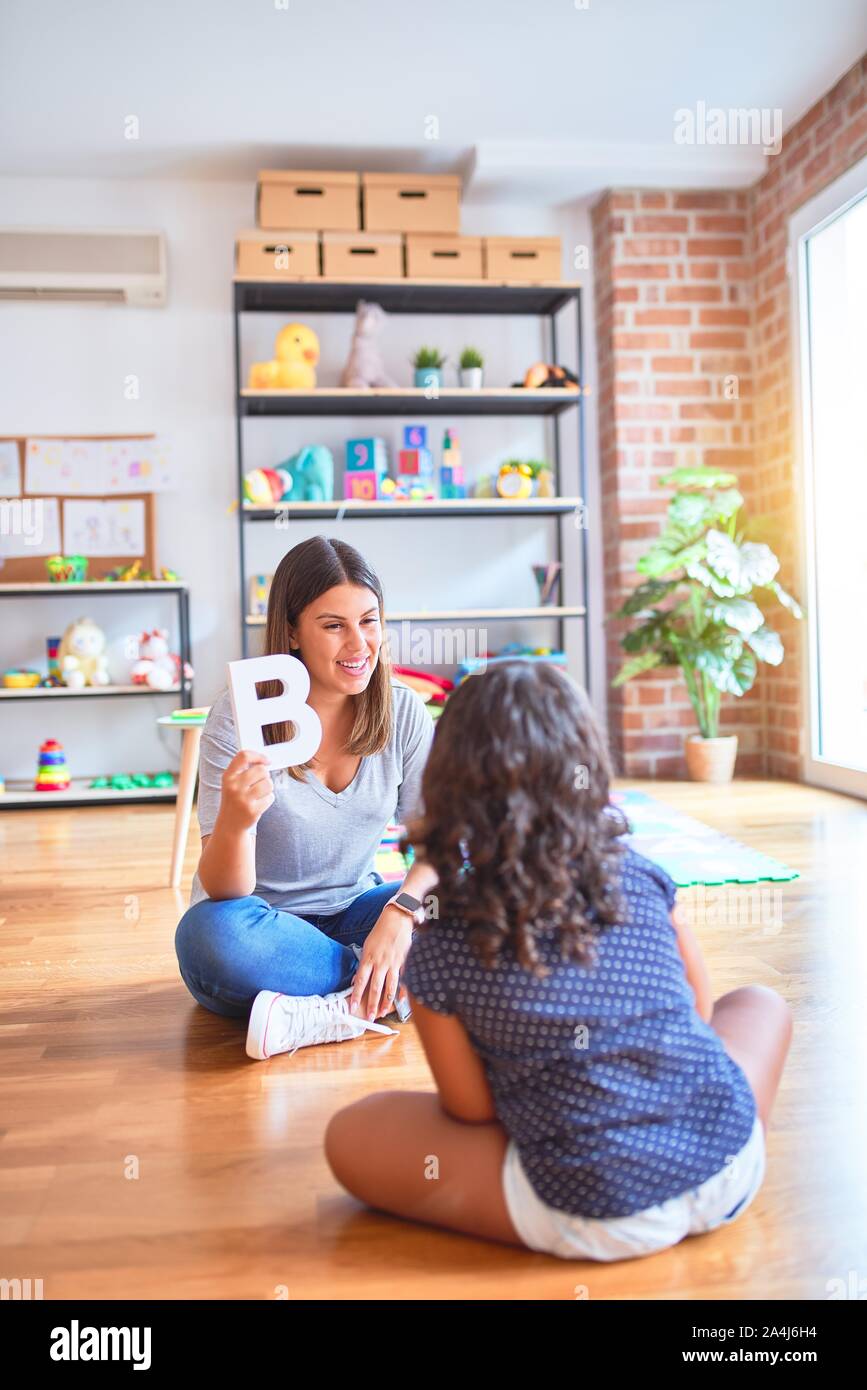 Beautiful teacher teaching alphabet to student toddler girl at ...