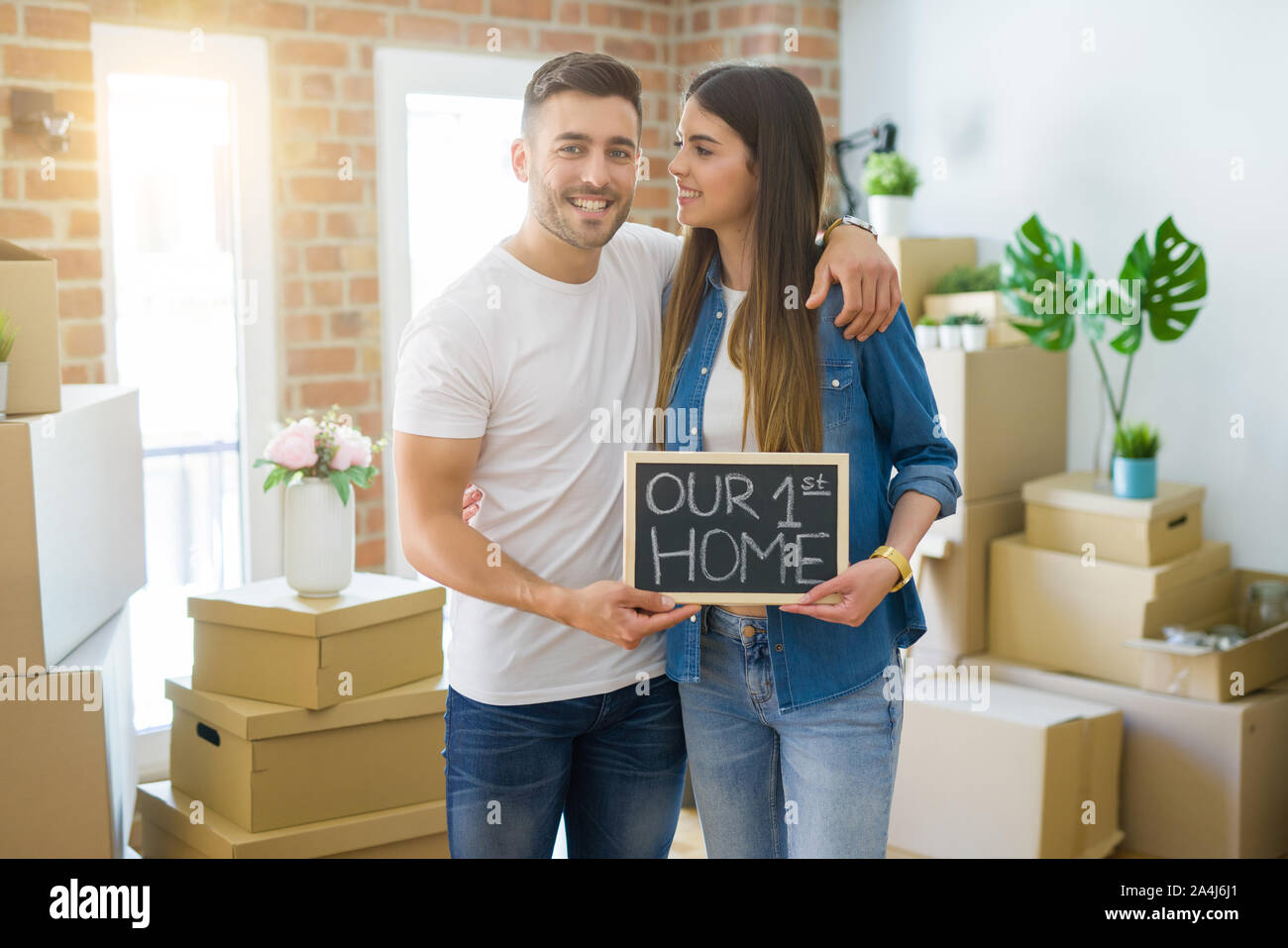 Beautiful young couple moving to a new house, smiling very happy ...