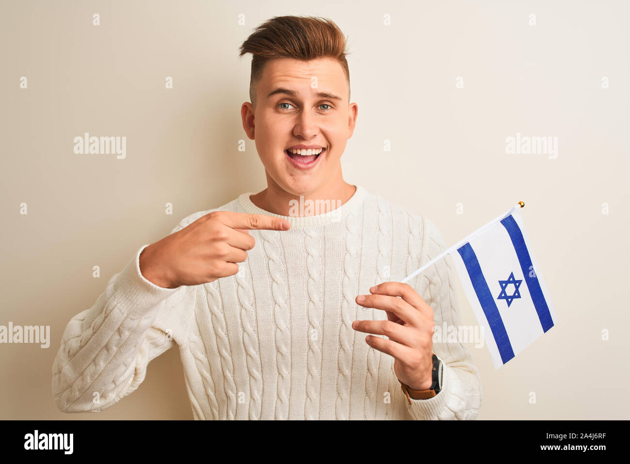 Young handsome man holding Israel Israeli flag over isolated white ...