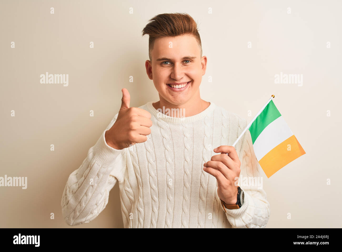 Young handsome man holding Ireland Irish flag over isolated white ...