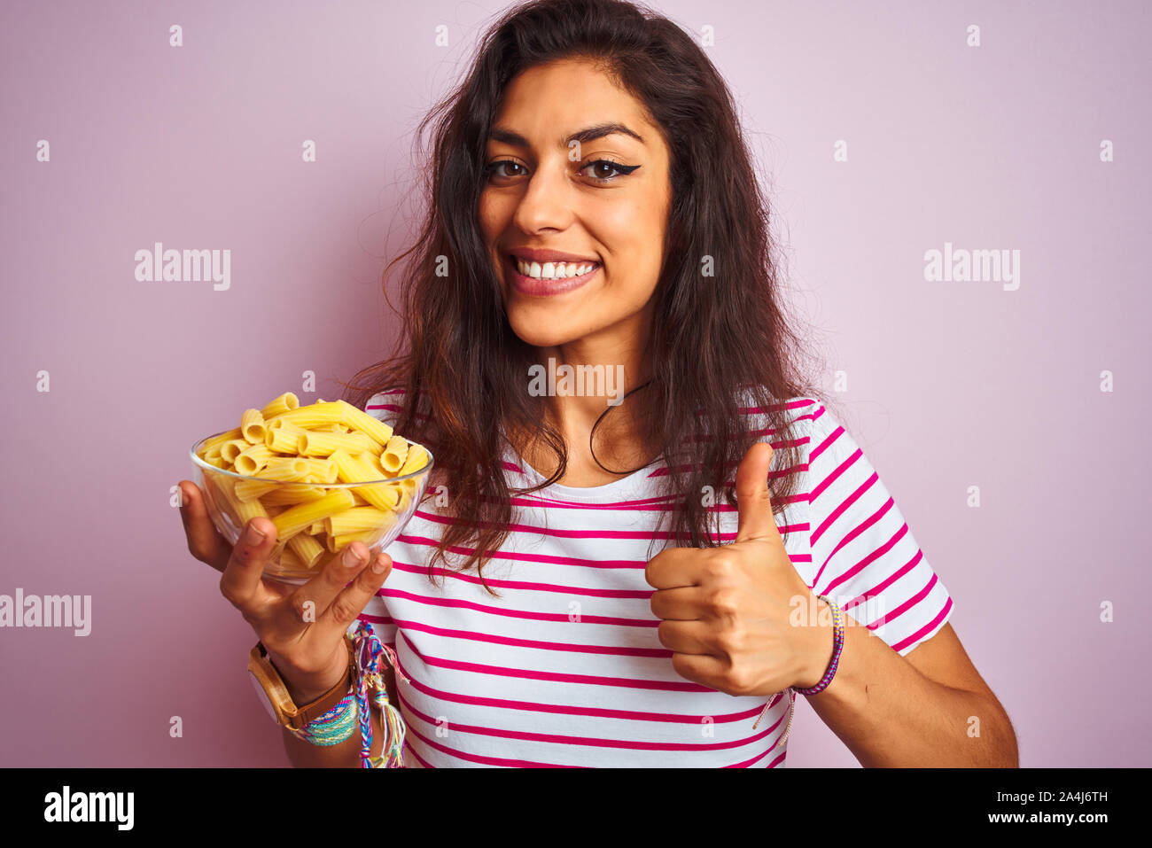 Young beautiful woman holding bowl with dry macaroni pasta over ...