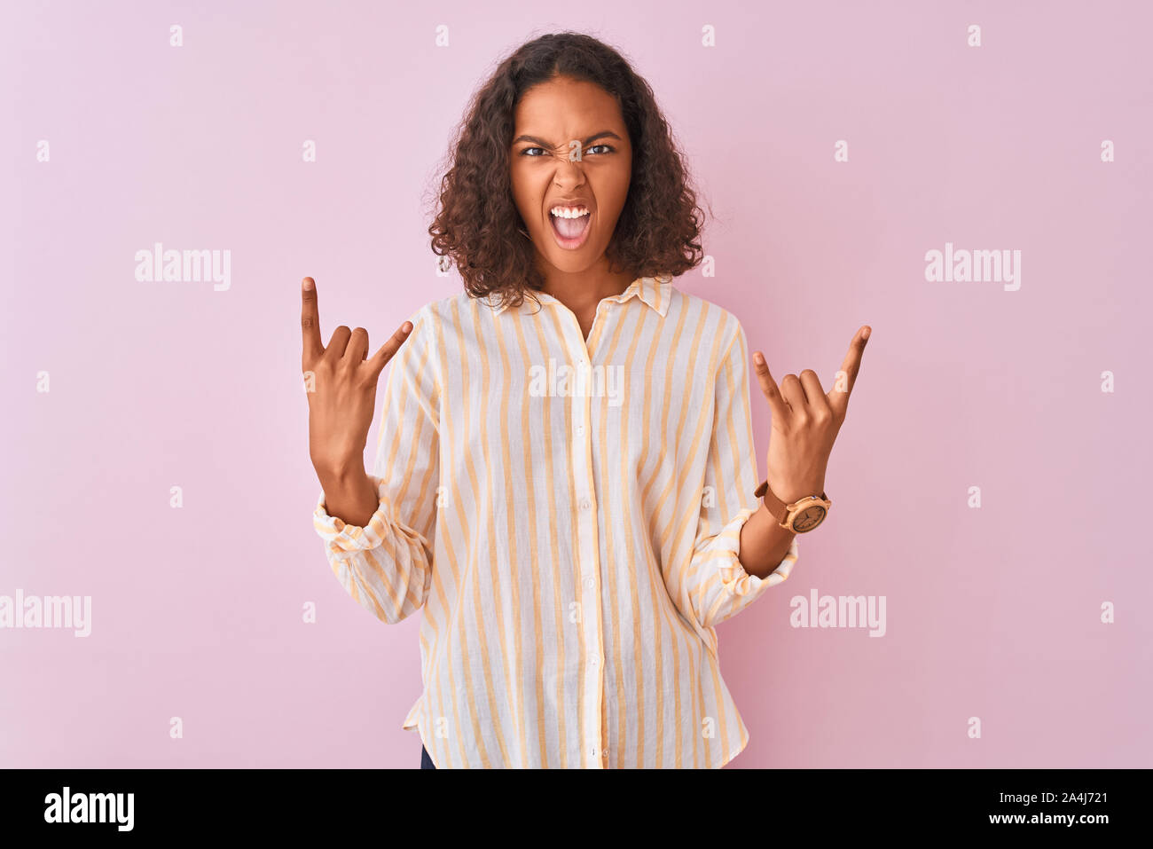 Young brazilian woman wearing striped shirt standing over isolated pink ...