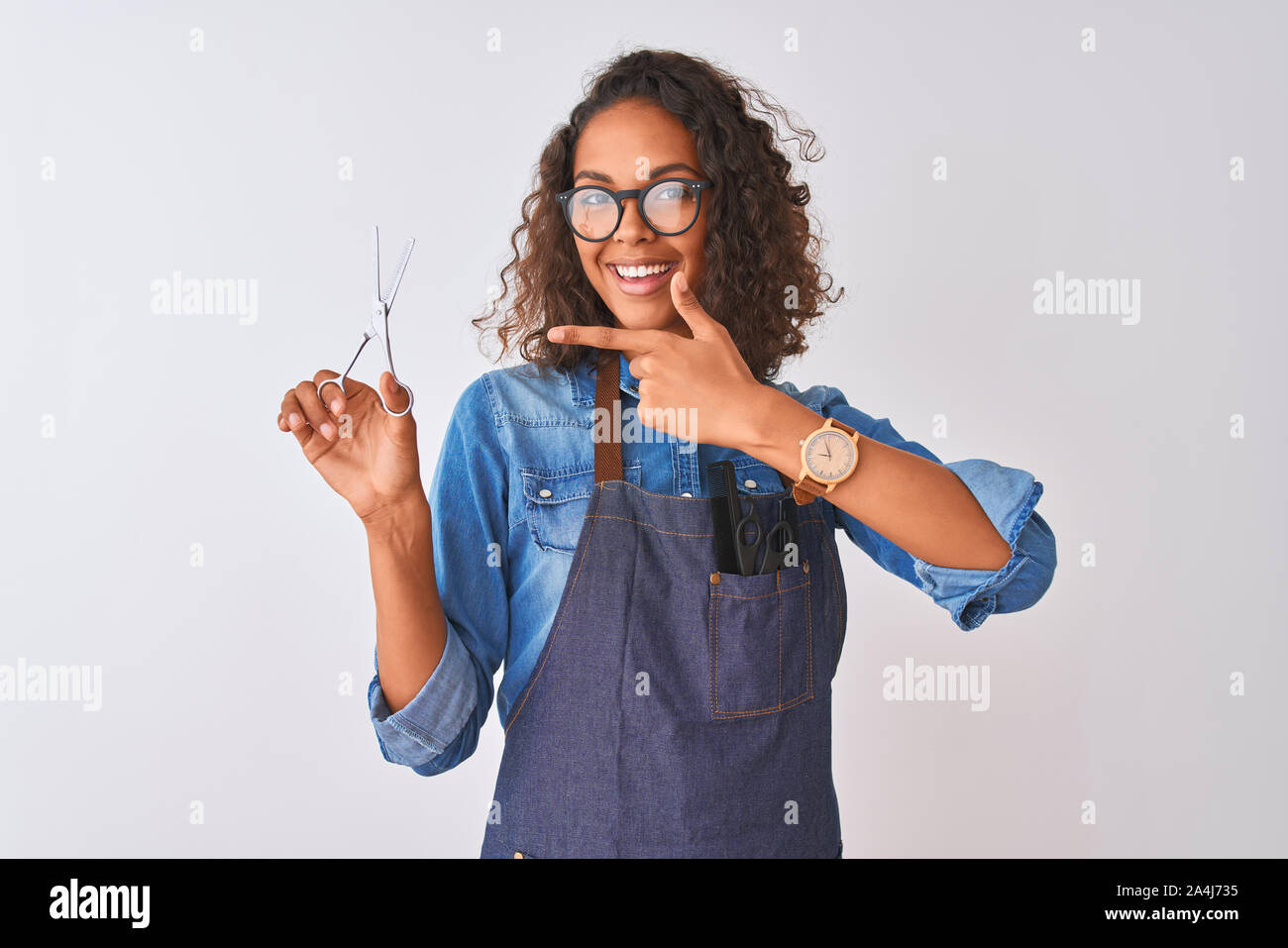Young brazilian hairdresser woman using scissors standing over isolated ...