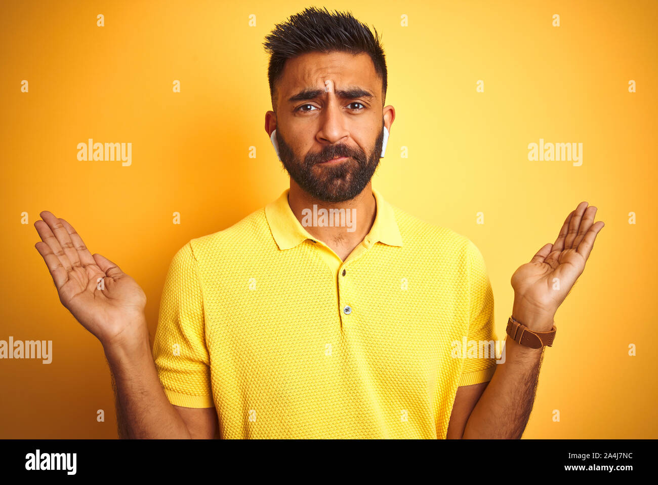 Young indian man listening to music using earphones standing over ...